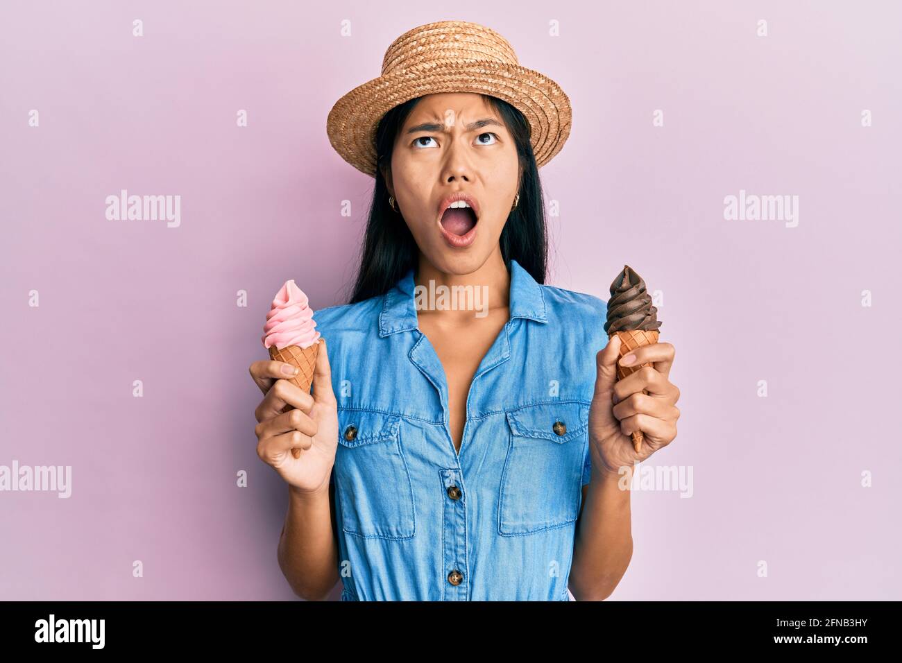 Young chinese woman wearing summer style holding ice cream angry and ...