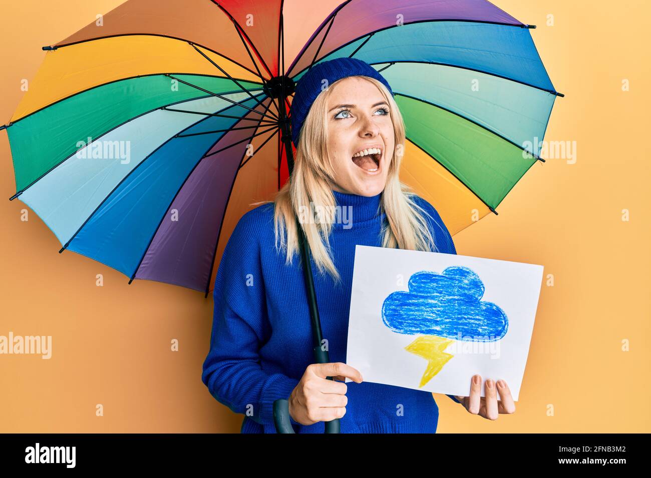 Young caucasian woman holding rain draw and umbrella angry and mad ...