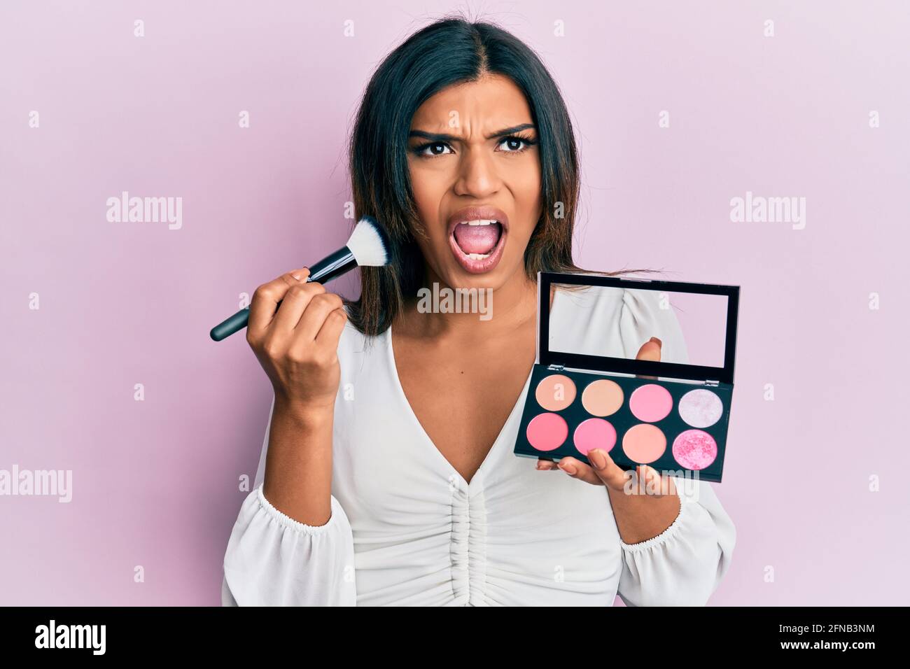 Young latin transsexual transgender woman holding makeup brush and ...