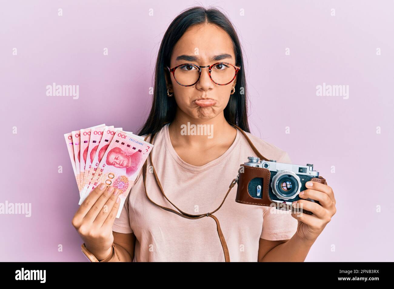 Young asian woman holding vintage camera and 100 chinese yuan depressed ...