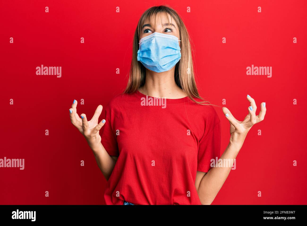 Teenager caucasian girl wearing medical mask crazy and mad shouting and ...