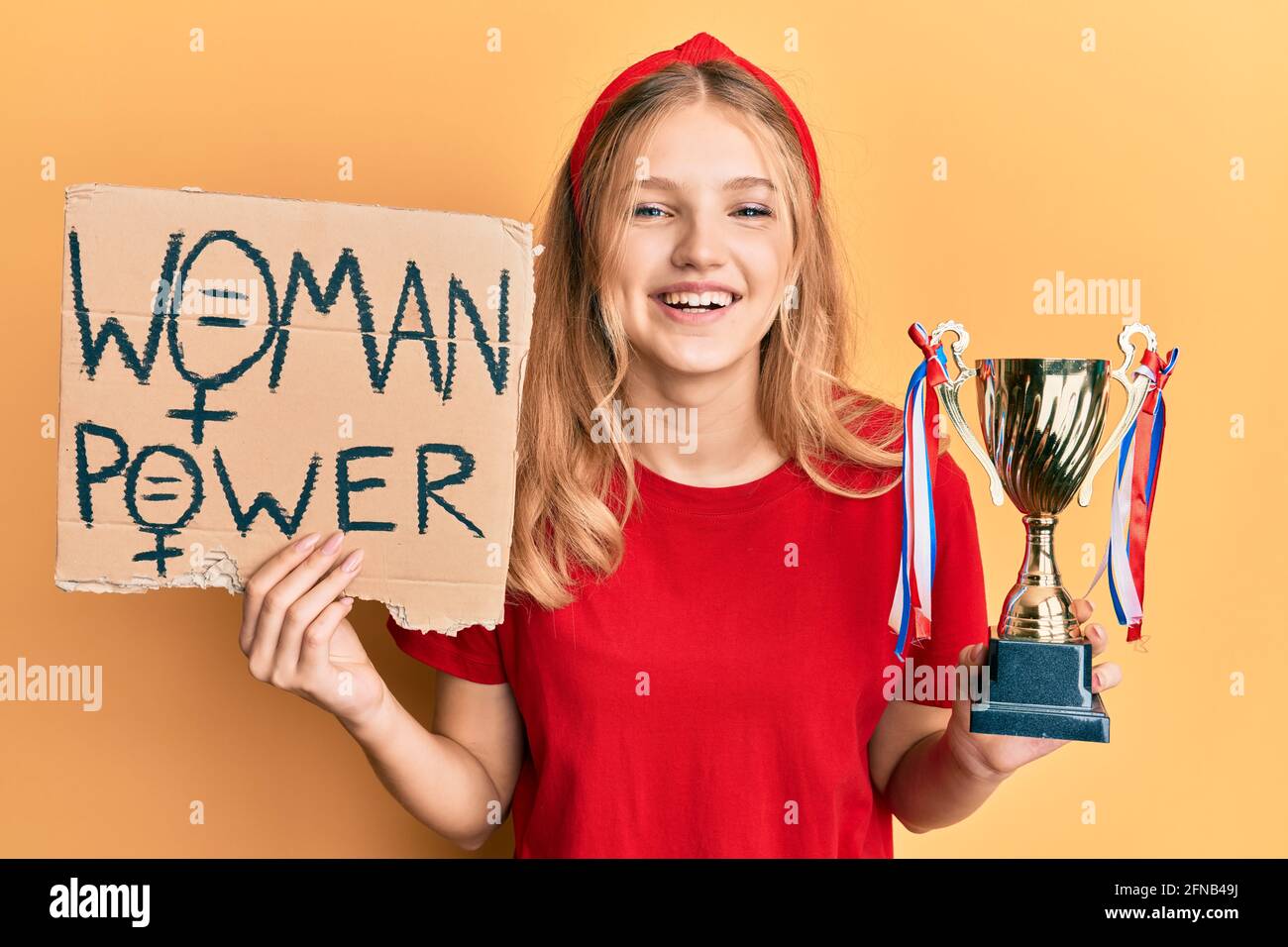 Beautiful young caucasian girl holding woman power banner and trophy ...