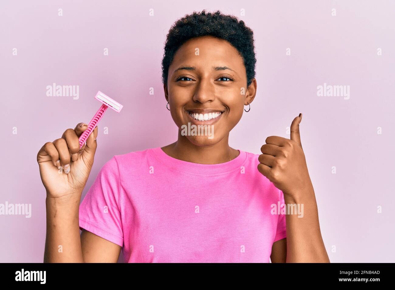 Young african american girl holding razor smiling happy and positive ...