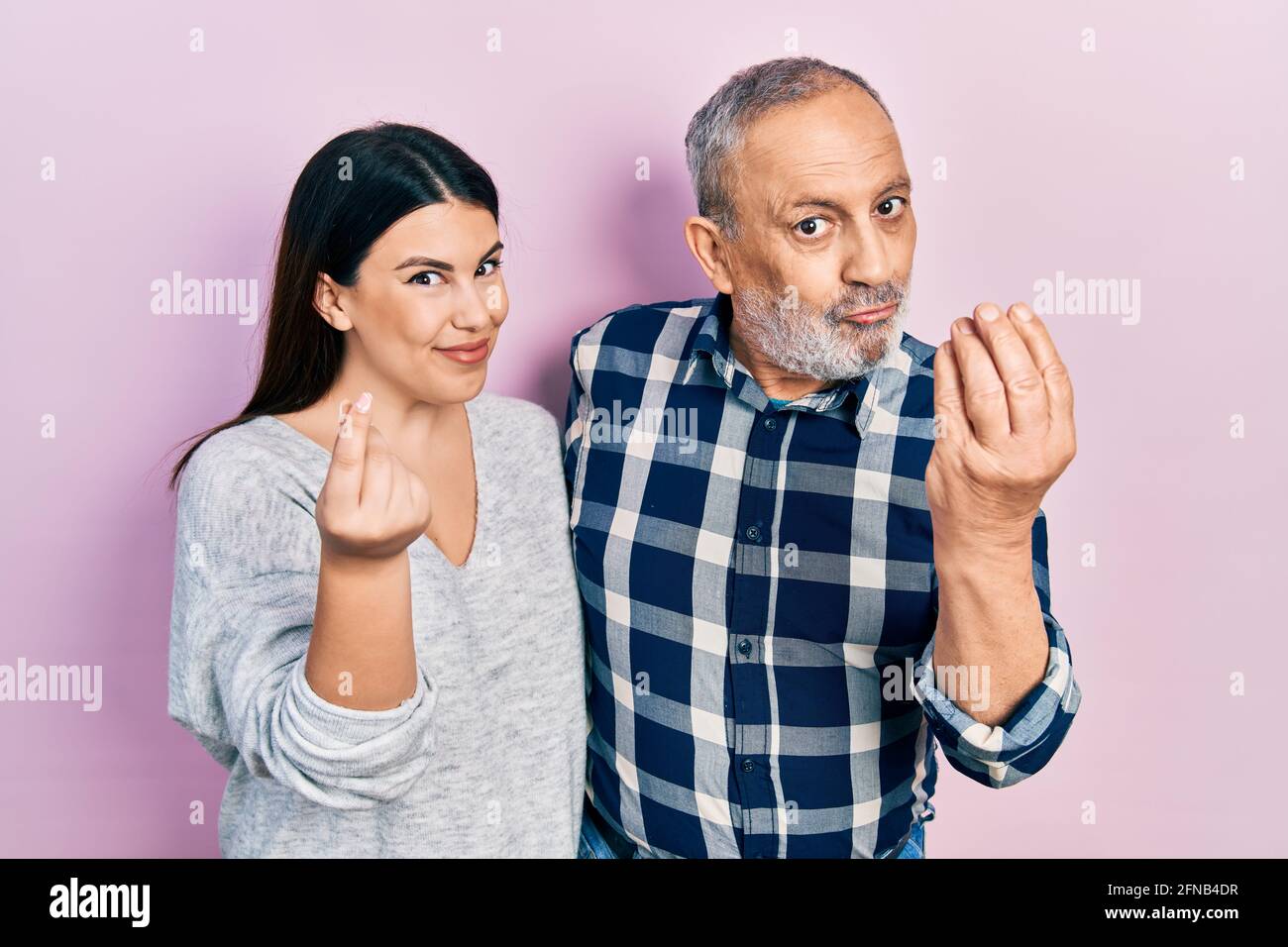 Hispanic father and daughter wearing casual clothes doing money gesture ...