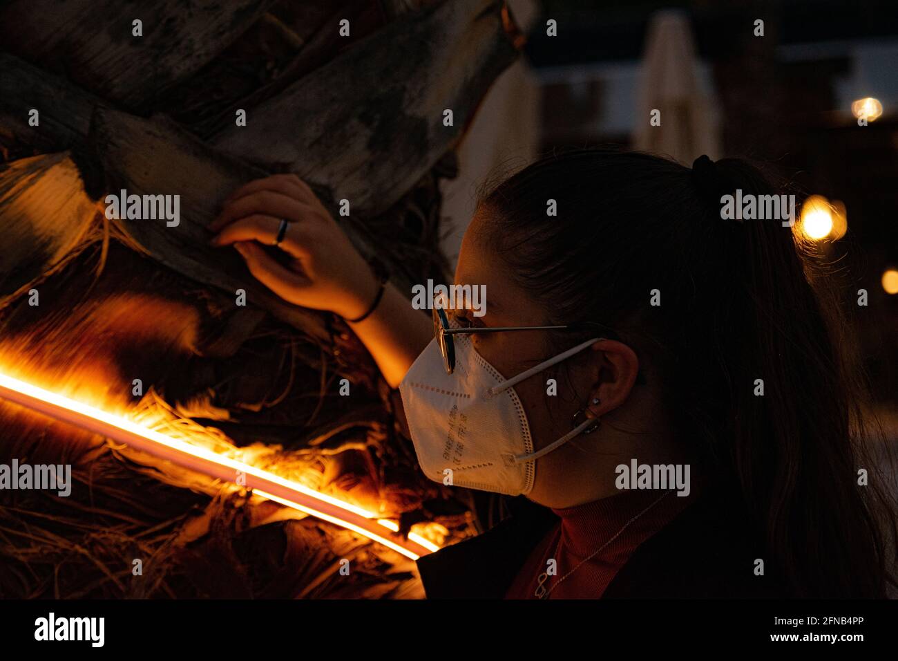 Beautiful girl lit by the leds of a palm tree Stock Photo - Alamy