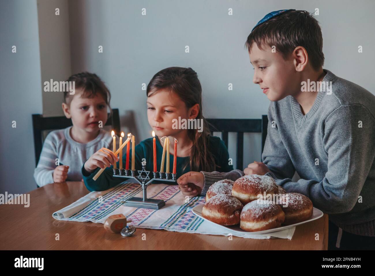 Brother and sisters siblings lighting candles on menorah for Jewish ...