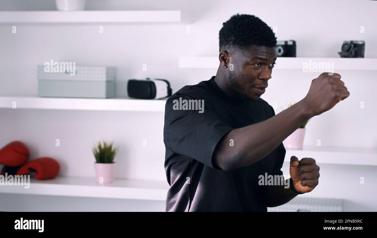 Black guy boxing in the air. Warm-up workout. White shelves mounted on ...