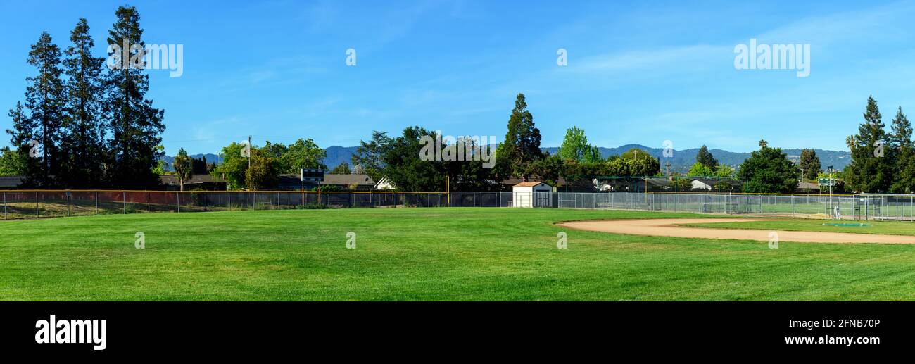 Panoramic view of an empty softball, baseball field, trees and green ...