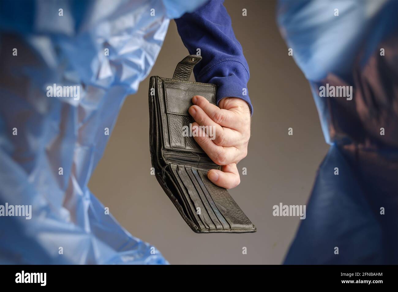A hand tosses an old black wallet into a trash can. Man holds empty ...