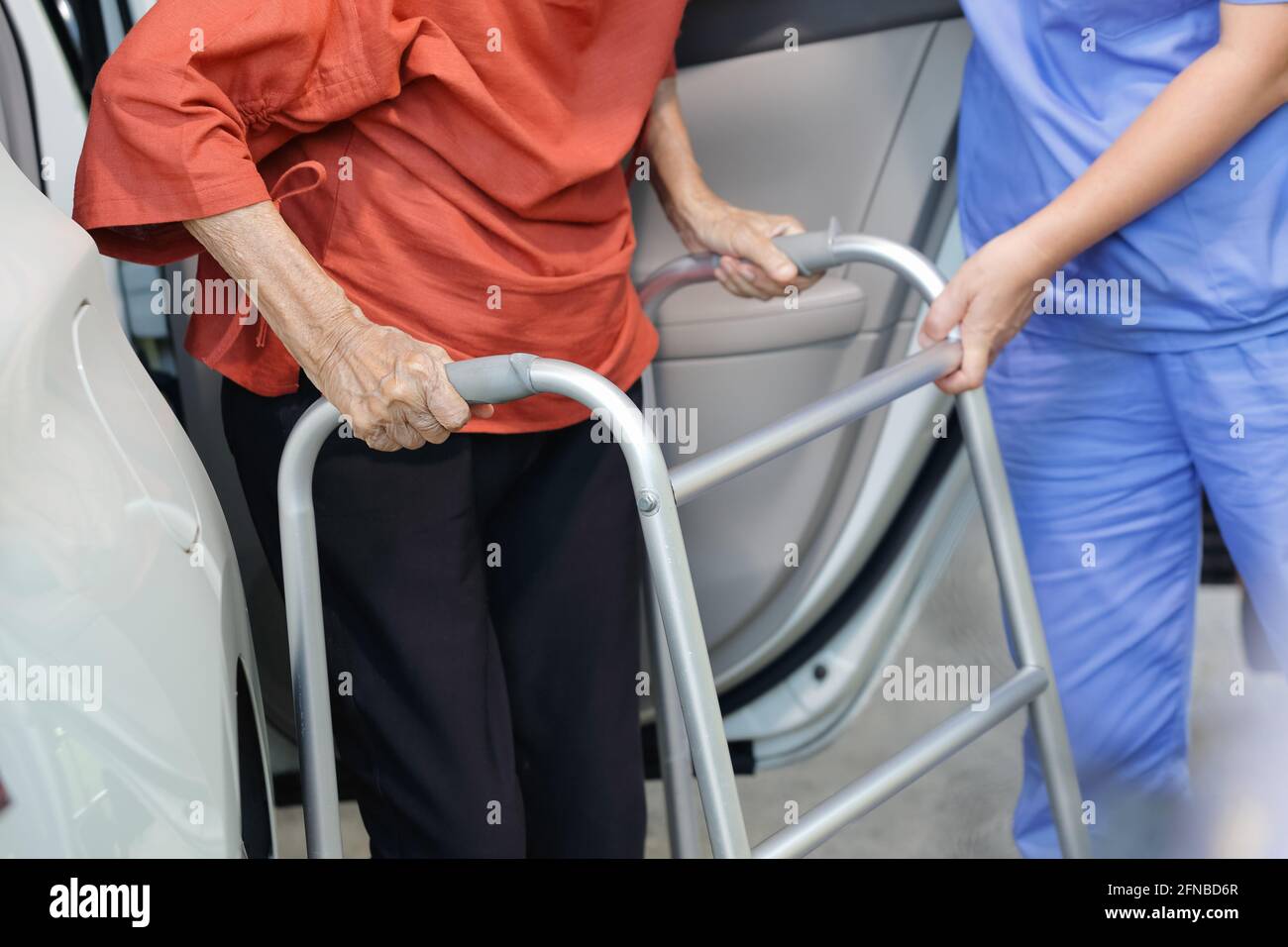 Elderly female using walker while get out of car with caregiver Stock ...