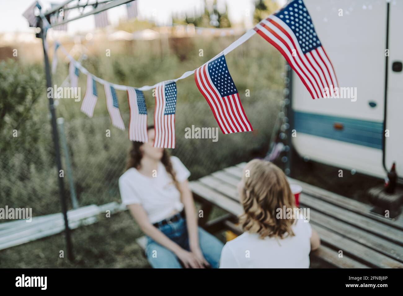 A closeup shot of small American flags hanging and women sitting near ...