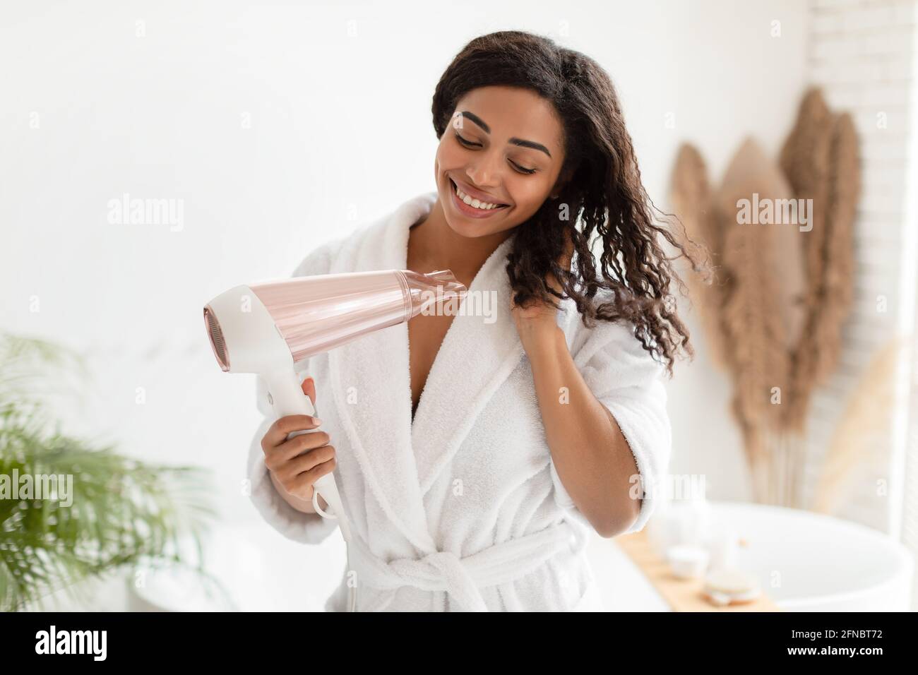 Happy Black Lady Drying Wavy Hair With Hairdryer In Bathroom Stock ...