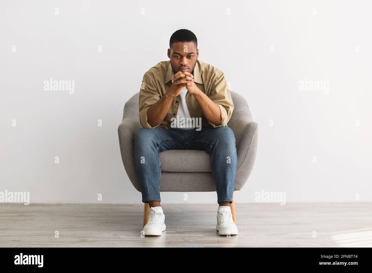 Thoughtful African Man Thinking Sitting In Chair Over Gray Background ...