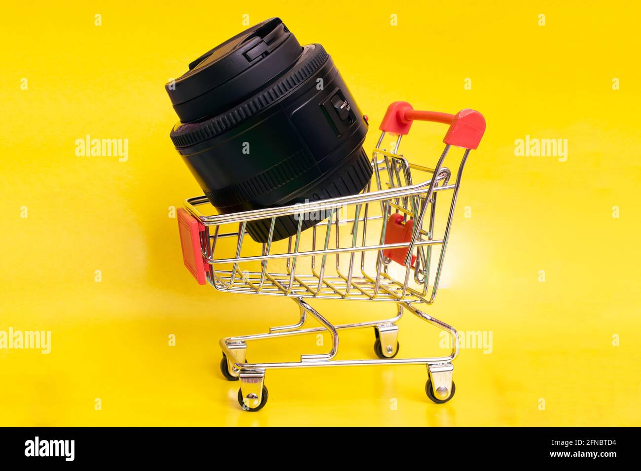 Camera lens in shopping trolley close up on yellow background Stock ...