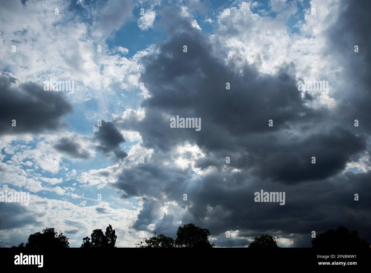Dark grey storm clouds building. Shafts of light pierce the clouds ...