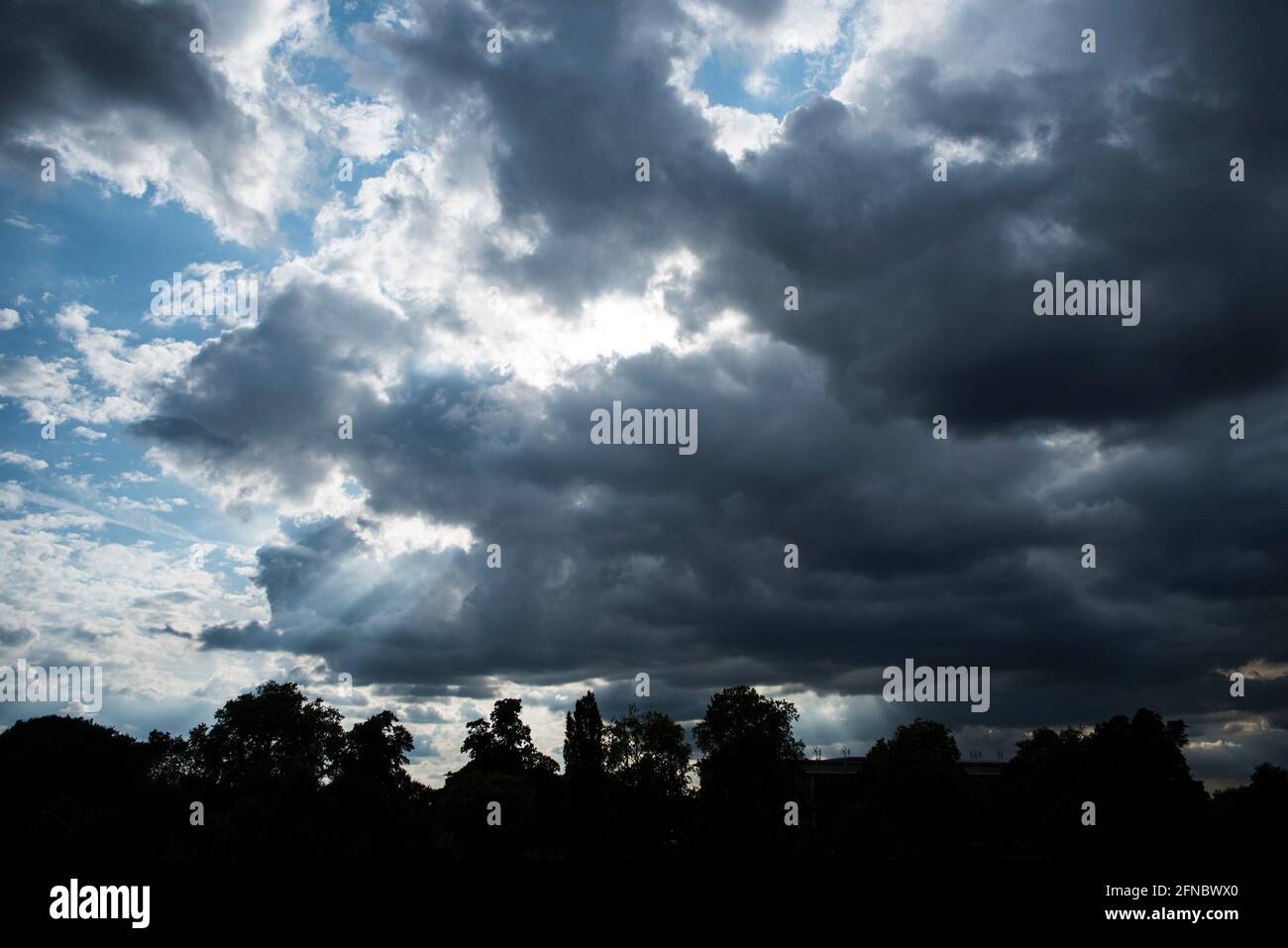 Dark grey storm clouds building. Shafts of light pierce the clouds ...