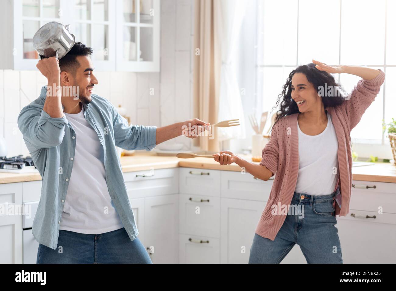 Domestic Fun. Cheerful arab couple playfully fighting in kitchen Stock ...