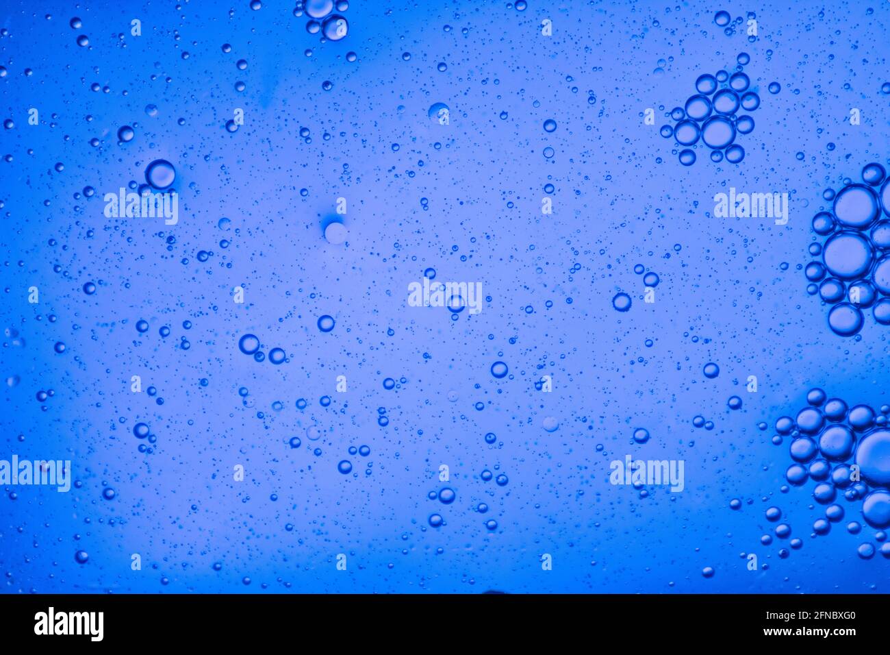 close-up view of a bright blue liquid background of moving bubbles ...
