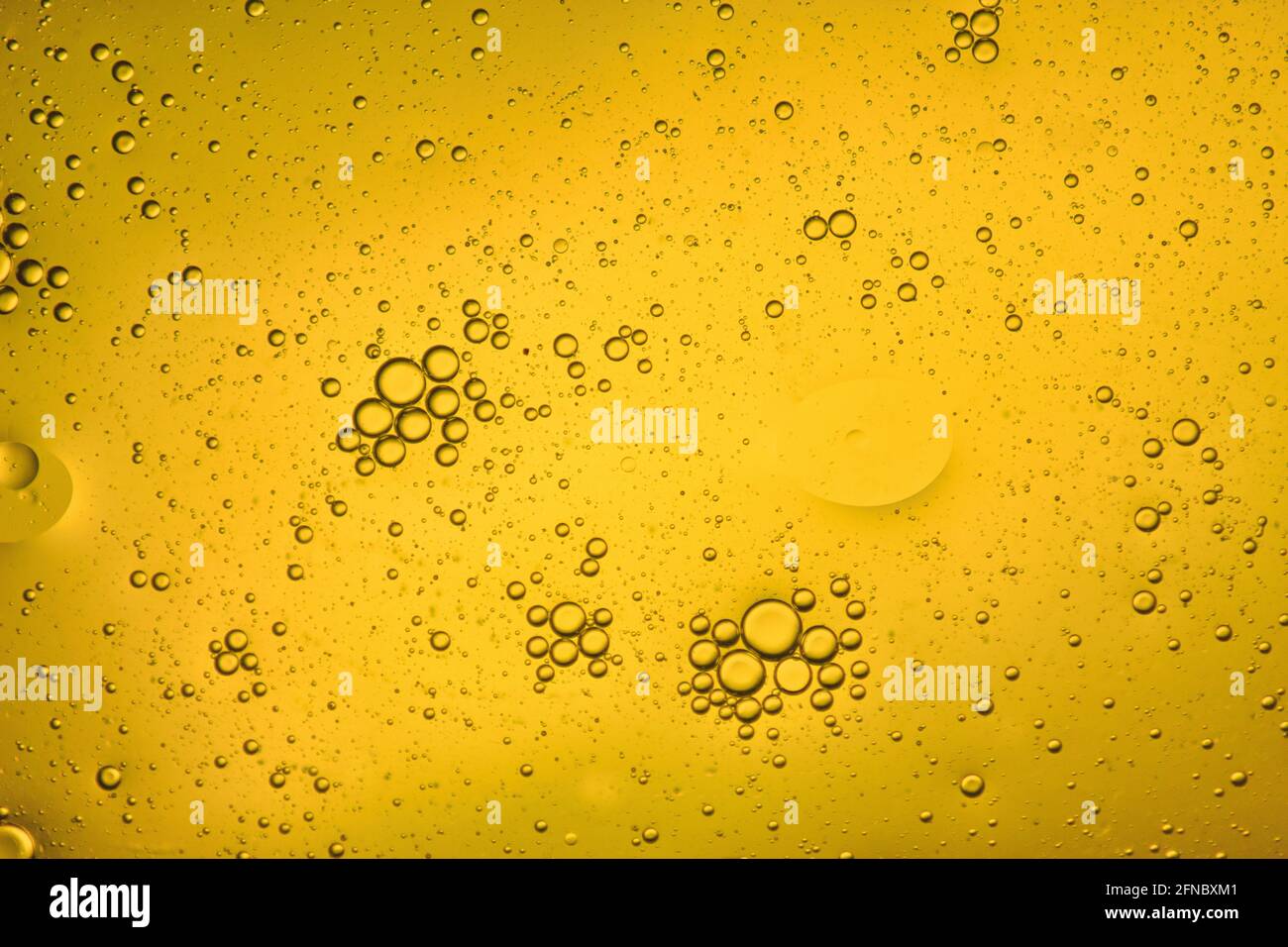 close-up view of a light yellow liquid background of moving bubbles ...