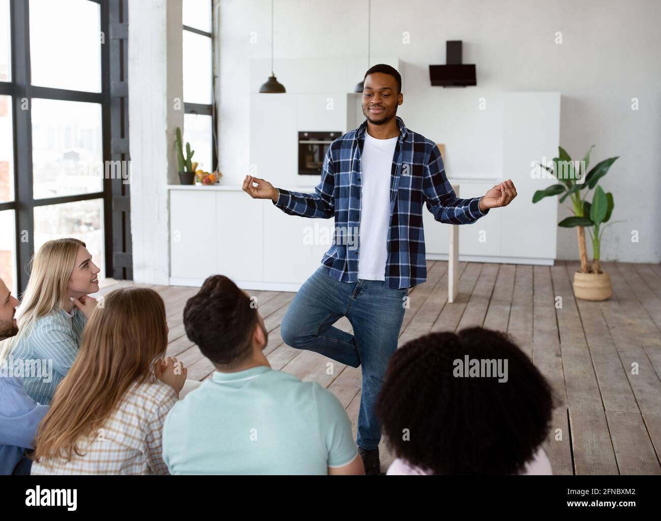 Happy black guy showing pantomime to his multiracial friends, playing ...
