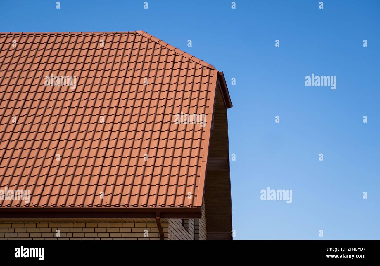 Red corrugated metal profile roof installed on a modern house. The roof ...