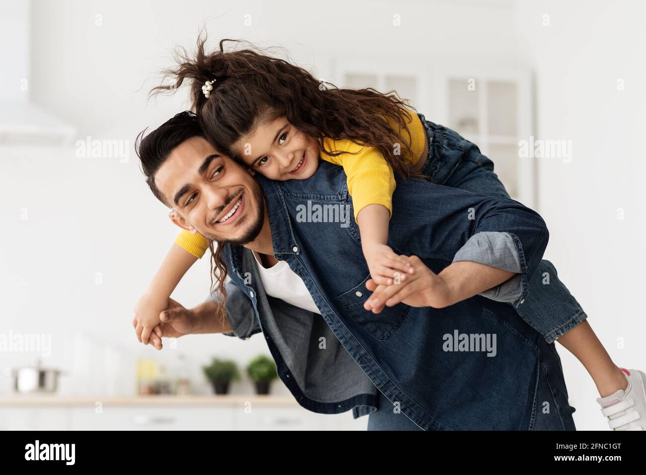 Cheerful arab dad carrying his cute little daughter on back and laughing Stock Photo - Alamy