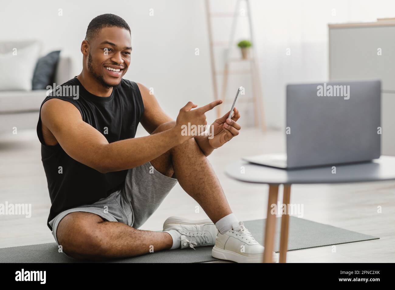 Black Fitness Guy Showing Smartphone To Laptop Recommending Application ...