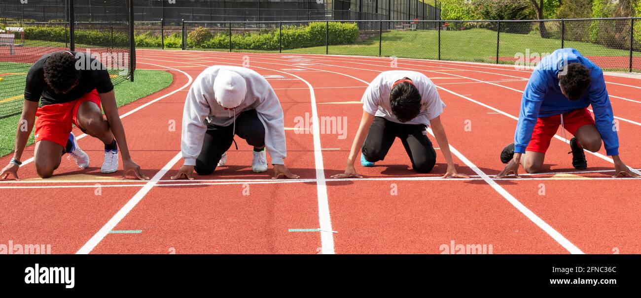 Front view of four high school boys sprinters ready on their mark to ...