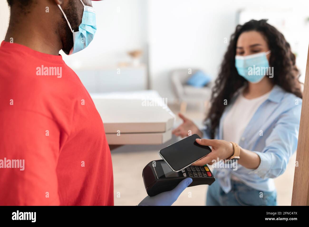 Black man holding POS machine client paying with smartphone Stock Photo ...