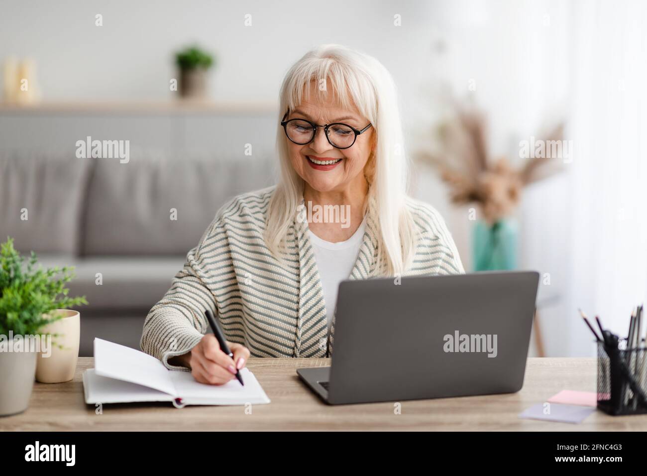Smiling mature woman writing hi-res stock photography and images - Alamy