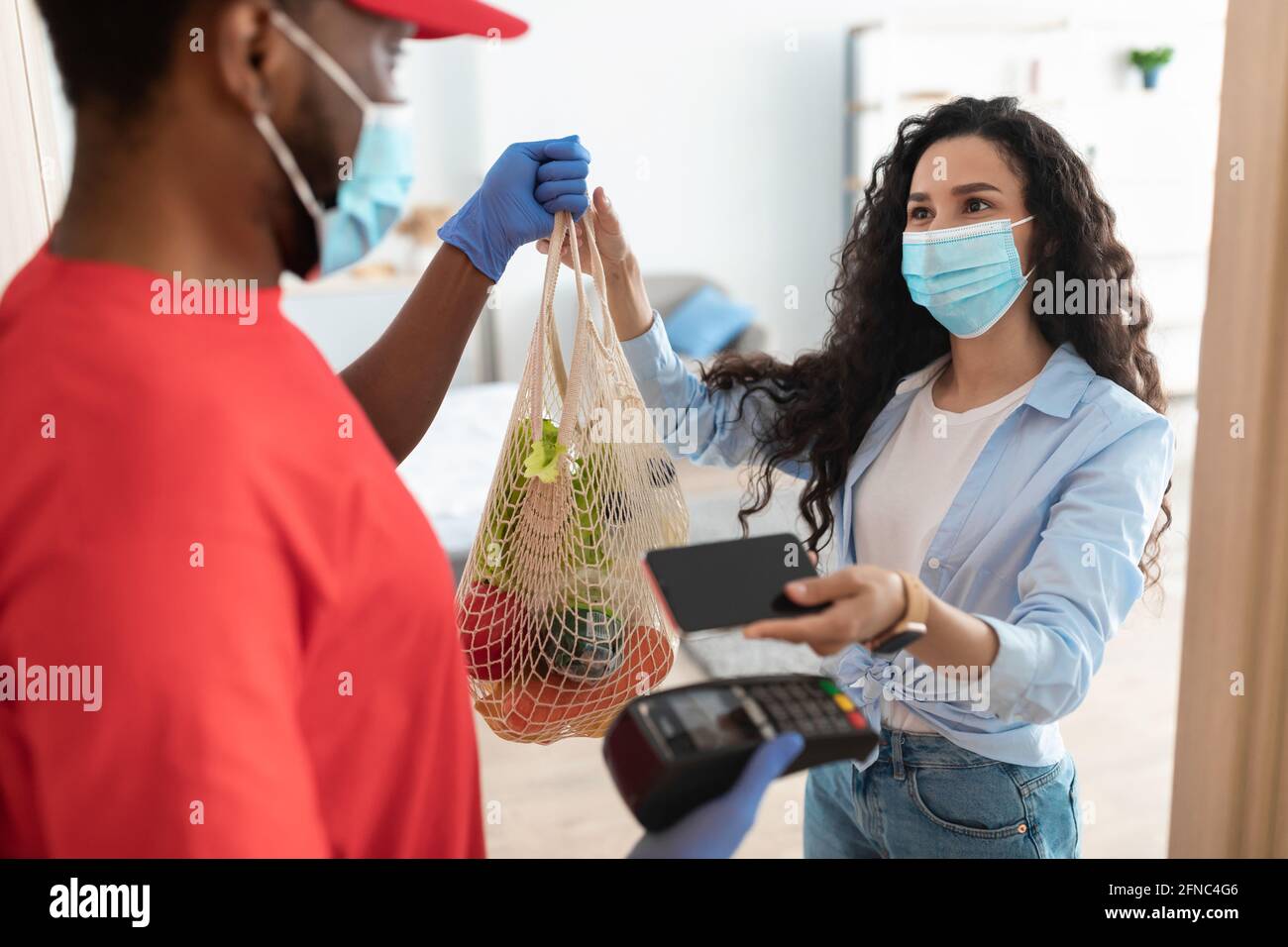 Black delivery man holding POS machine for payment Stock Photo - Alamy