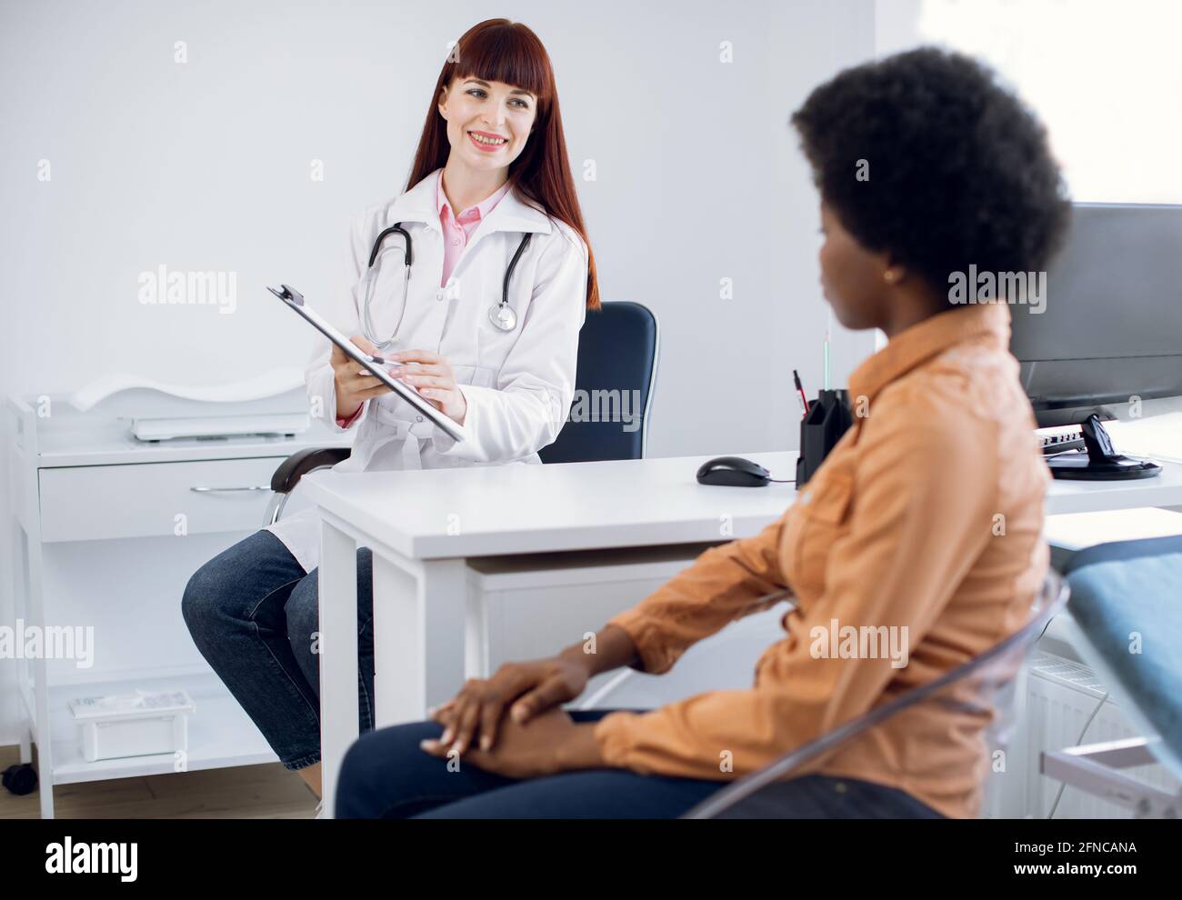 Black African female patient consulting with young confident European ...