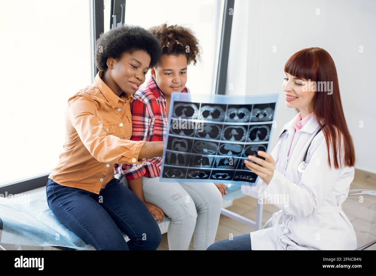 Young female European gp pediatrician, explaining X-ray tomography scan ...