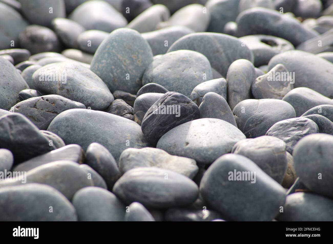 Round stones on a dry river bed outside in nature. Smooth pebbles with ...