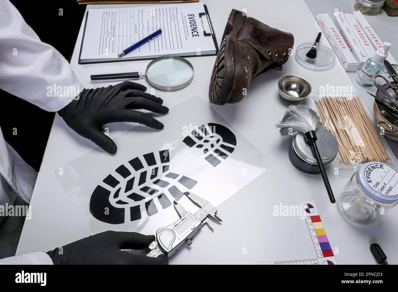 Police scientist investigates with a scale on a shoe sole tape tread ...