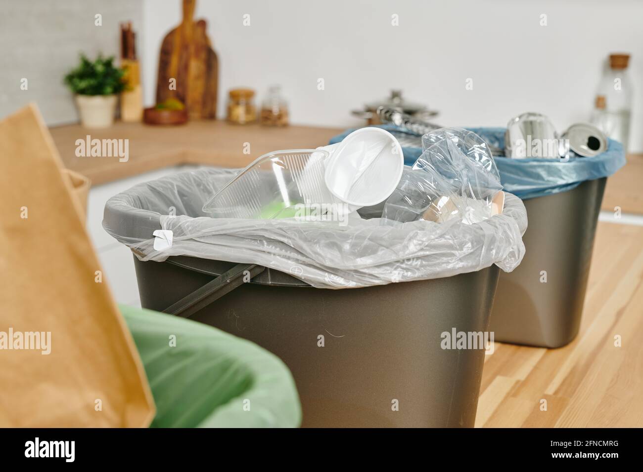 A plastic bag with used disposable kitchenware and other waste in trash ...