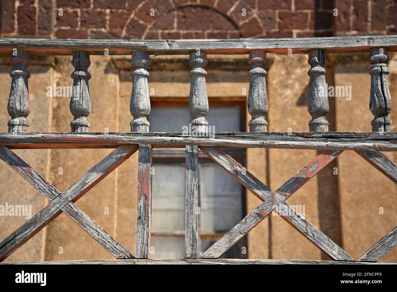 Antique handcrafted wooden railing with a stone wall in the background ...
