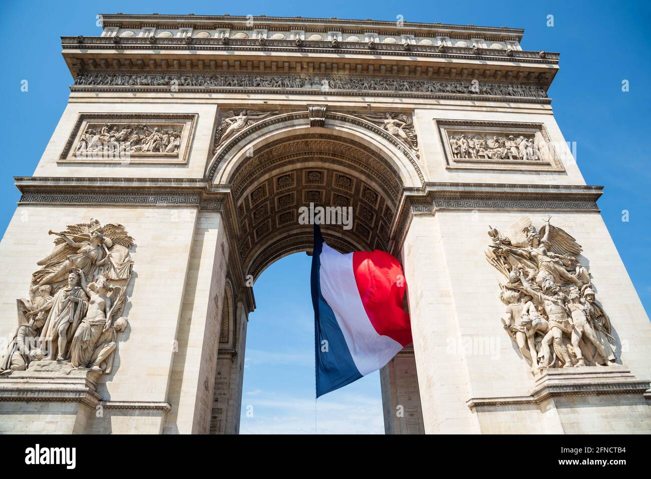 French flag waving under Arc de Triomphe in honor of VE day. Facade ...