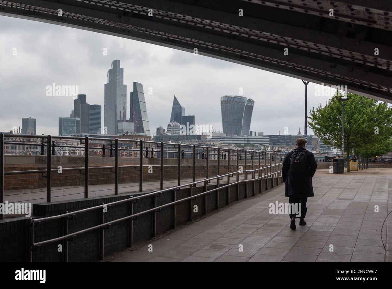 person walking under bridge with London skyline in backround Stock ...