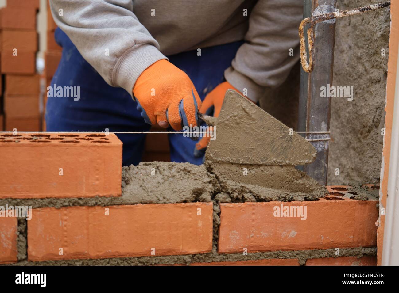 Construction worker putting cement on the brick wall. Man bricklaying ...