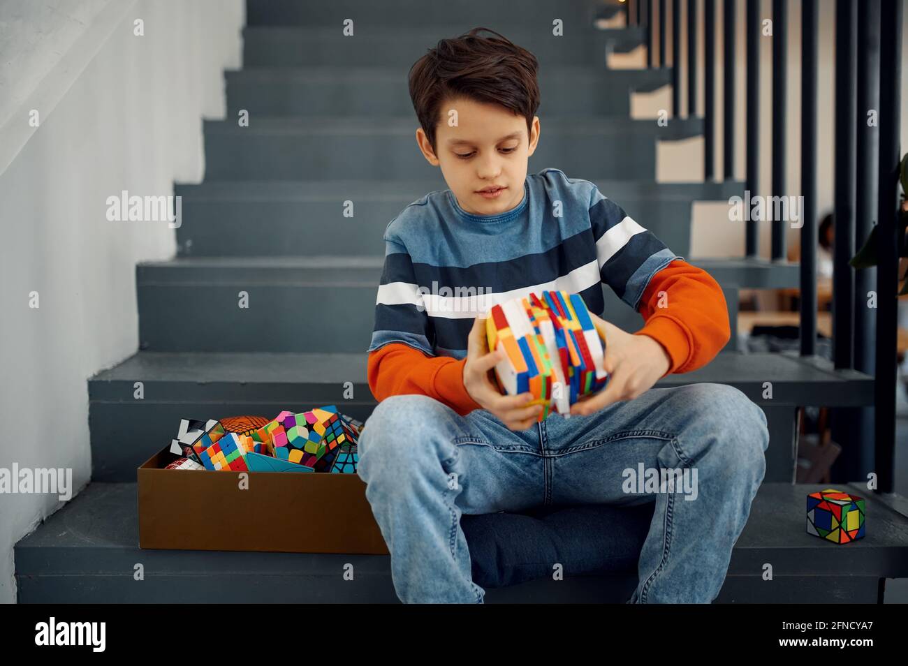 Boy sitting on steps and play with puzzle cubes Stock Photo - Alamy