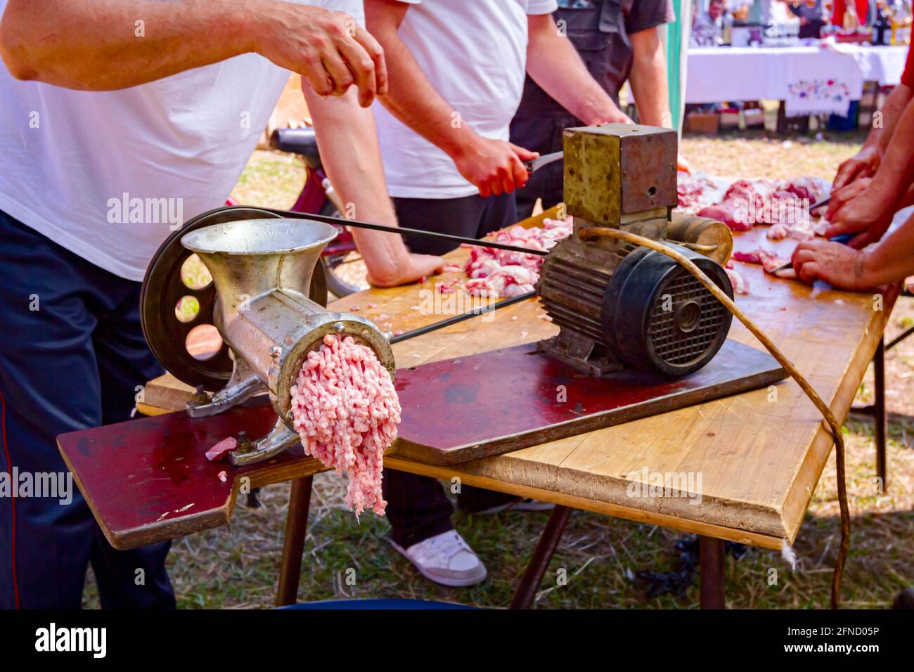 Men are working together on meat grinder machine, forcemeat process for ...