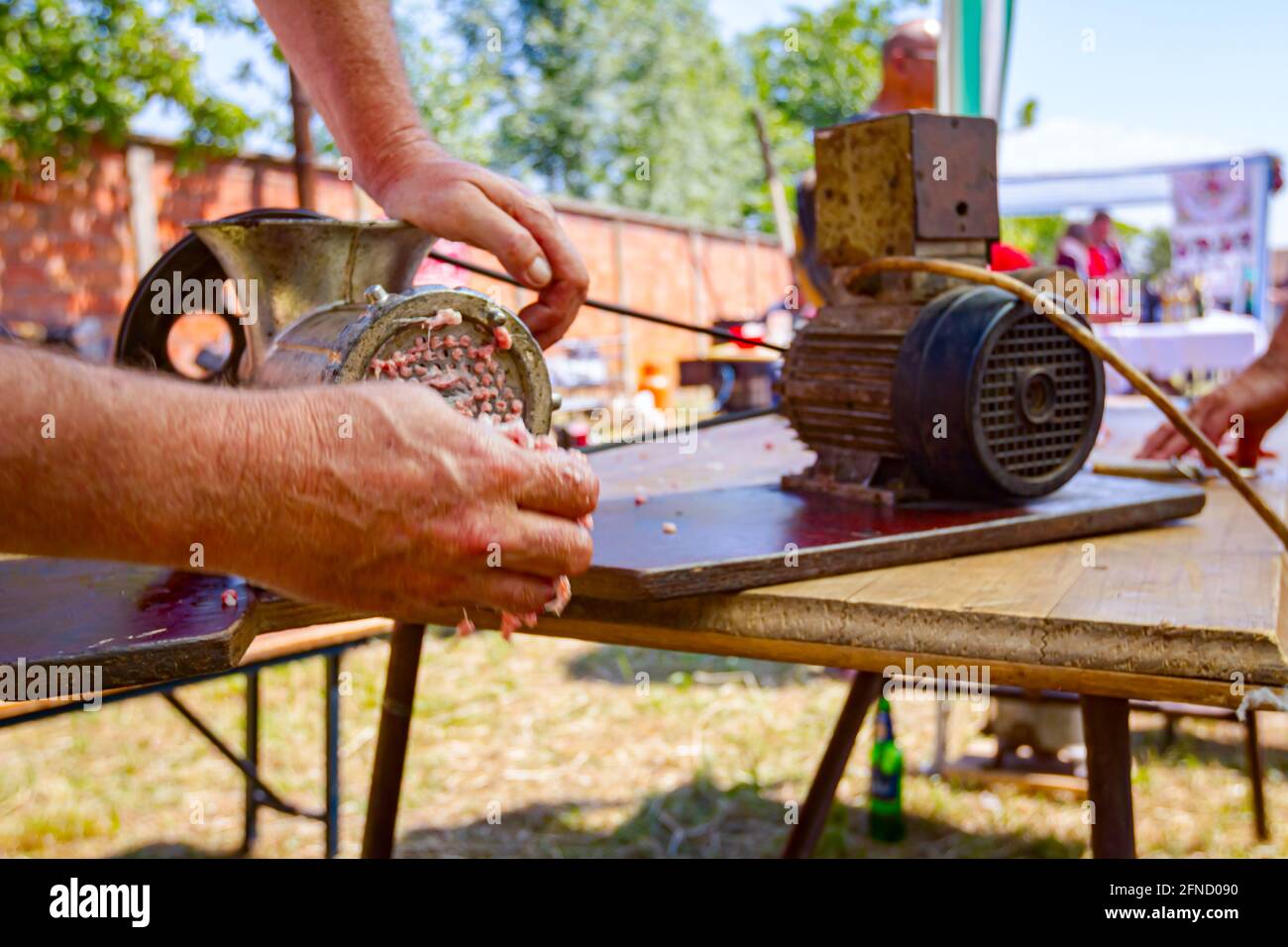 Men are working together on meat grinder machine, forcemeat process for ...