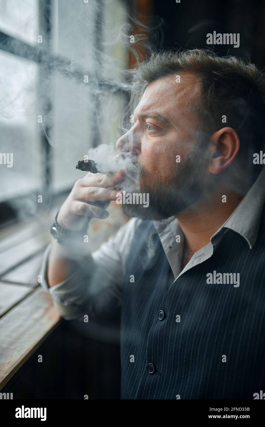 Man at the windowsill and smokes a cigar Stock Photo - Alamy