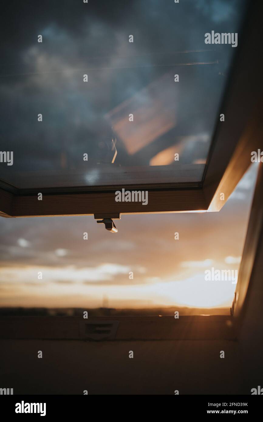 A vertical shot of a half-opened roof window with a sunset view Stock ...
