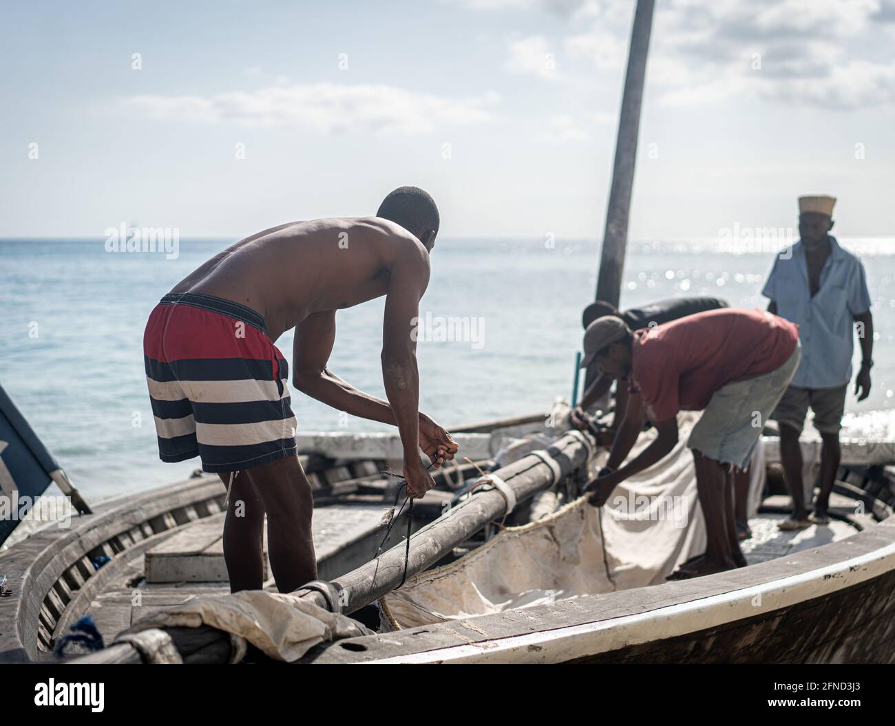 African men working on boat with the sail Stock Photo - Alamy