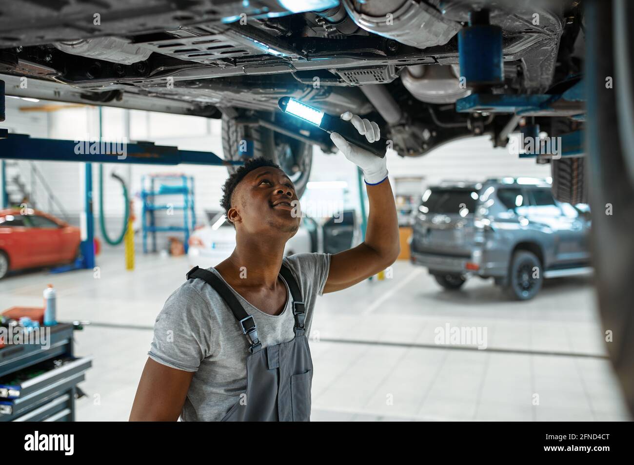 Male mechanic checks car suspension, auto service Stock Photo - Alamy