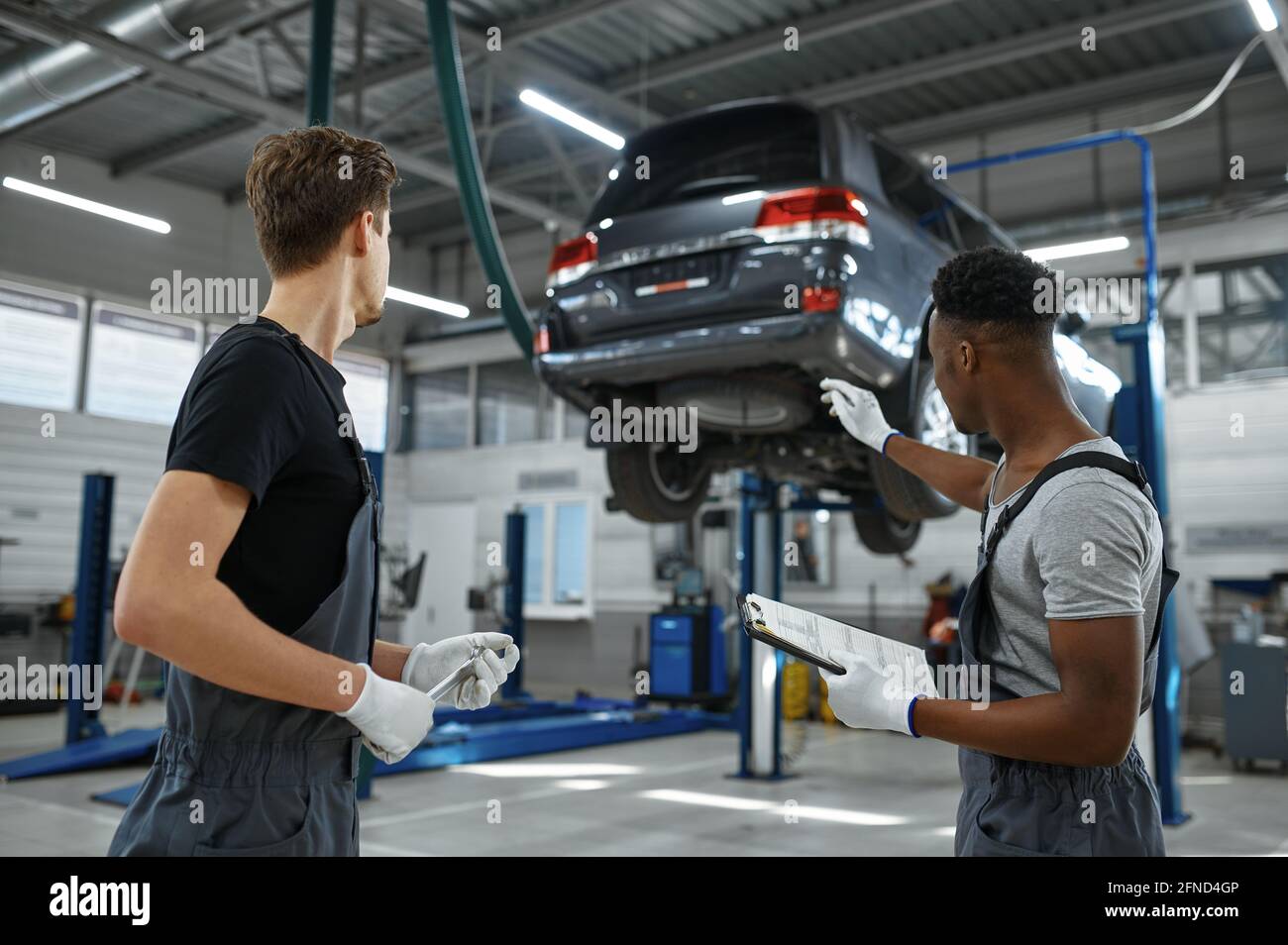 Two male mechanics talking in car service Stock Photo - Alamy