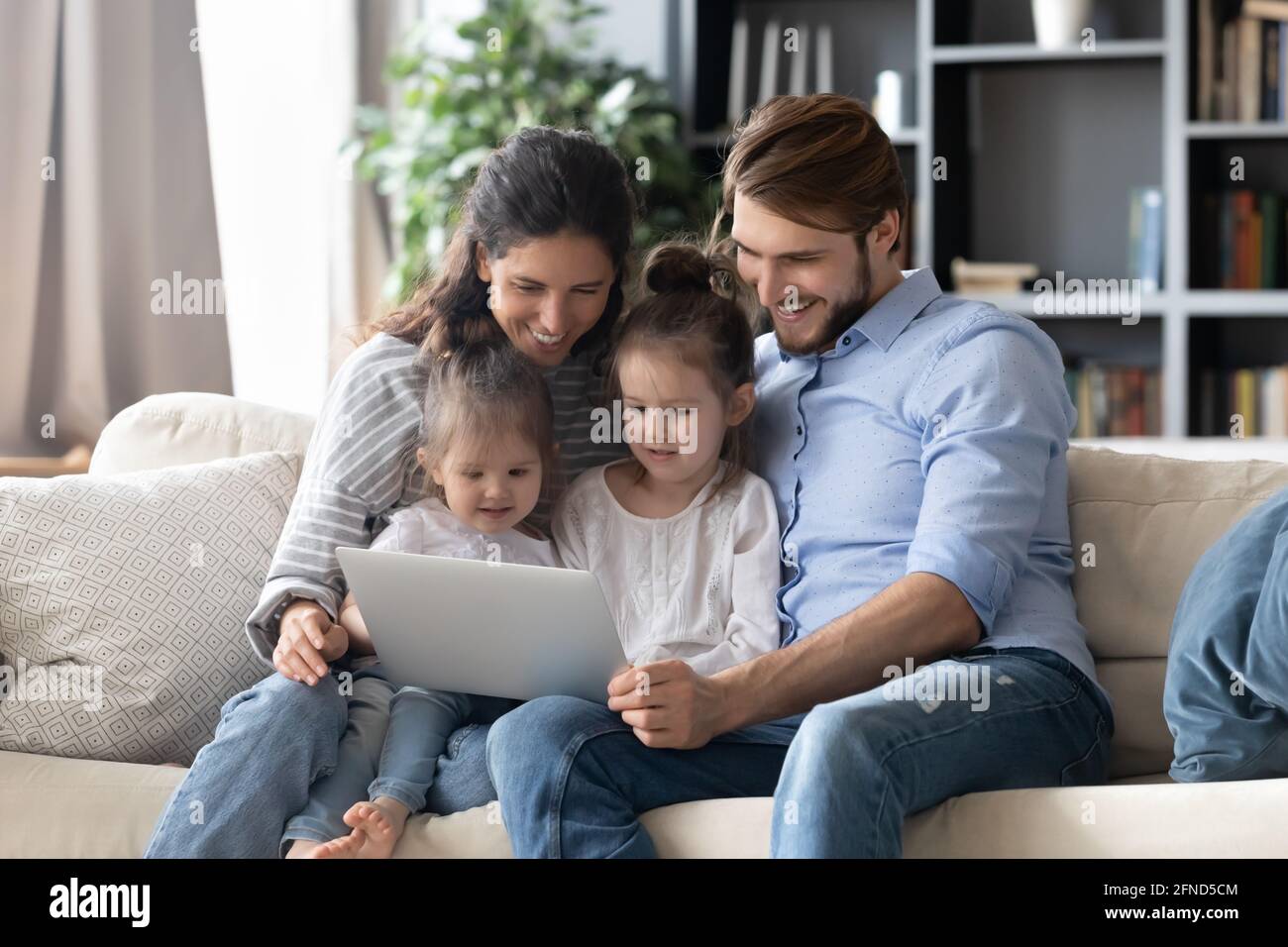 Happy parents and little daughters use laptop Stock Photo - Alamy