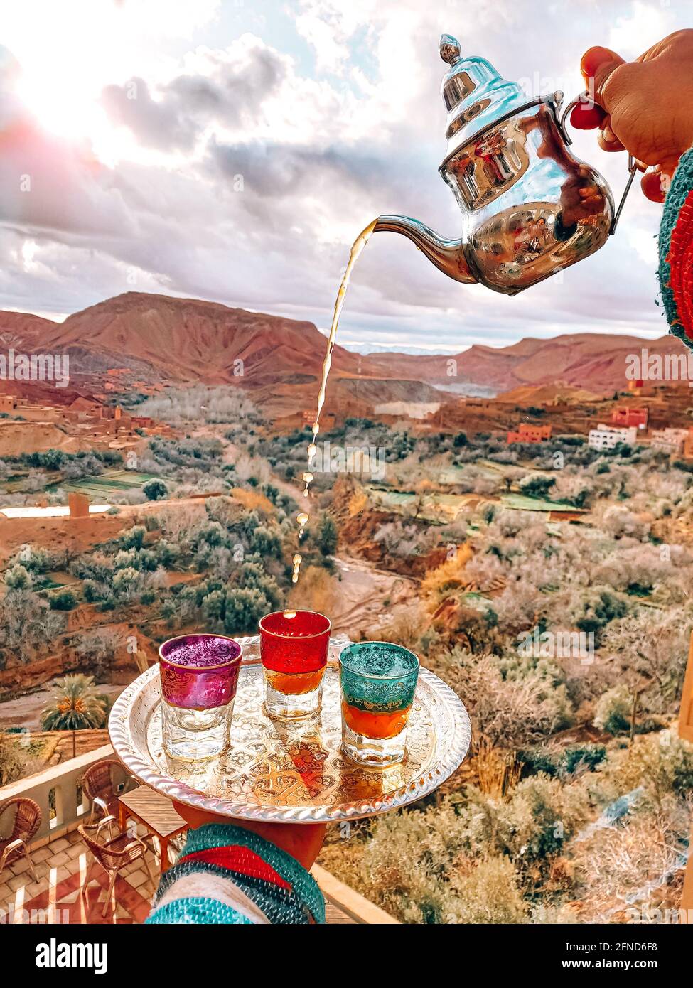 A hand pouring tea into a glass during Ramadan tea time in background ...